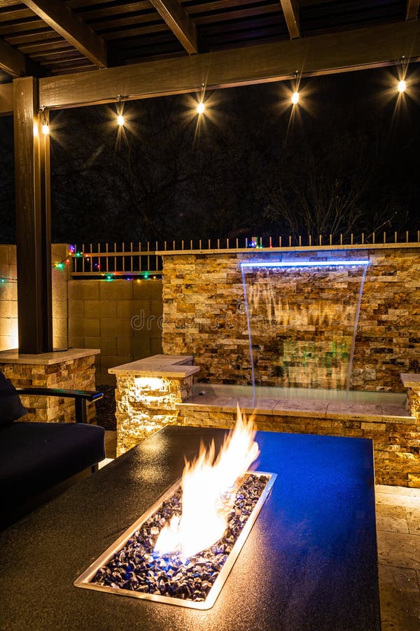 A Resort Style Backyard at Night with a Waterfall, Pergola, and a ...
