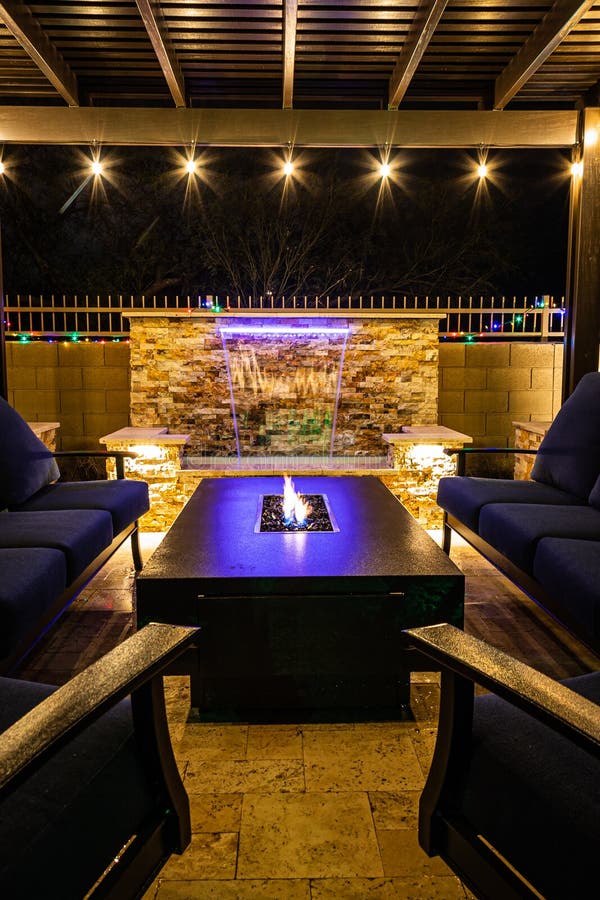 A Resort Style Backyard at Night with a Waterfall, Pergola, and a ...