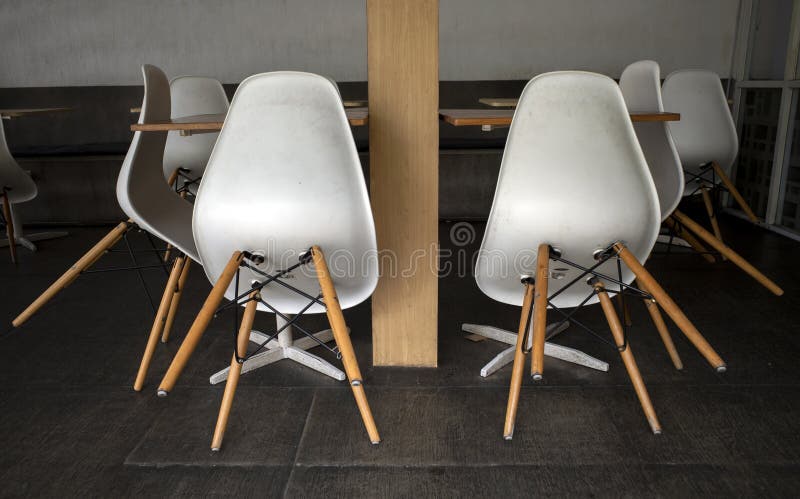 A Restaurant Closed with Wooden White Chairs Leaning Against a Table ...