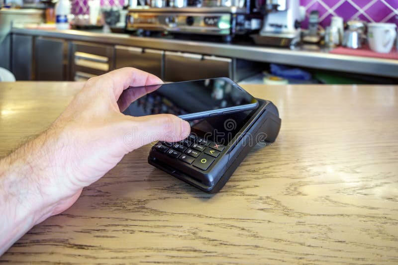 A Restaurant Customer Using a Smartphone To Pay at a Payment Terminal ...