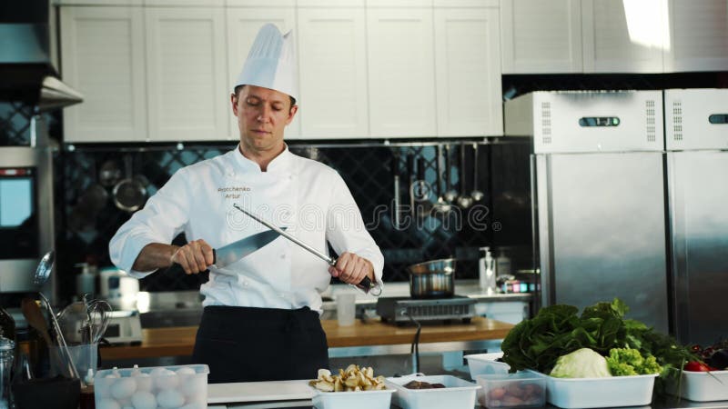 Restaurant Kitchen, Portrait of a Male Chef: Chef Sharpens Knives in a ...