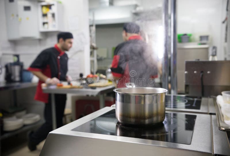 Restaurant Kitchen. Two Men Working on Serving Dishes. One Man Holding ...
