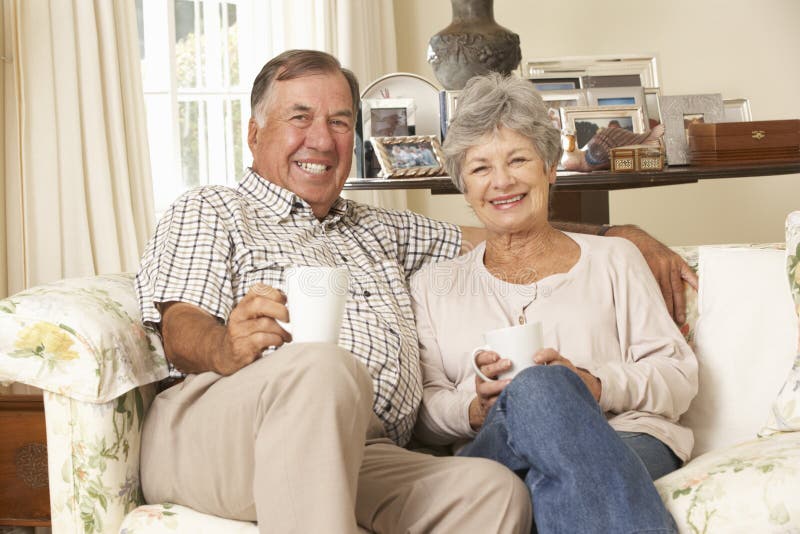 Retired Senior Couple Sitting on Sofa Drinking Tea at Home Together ...