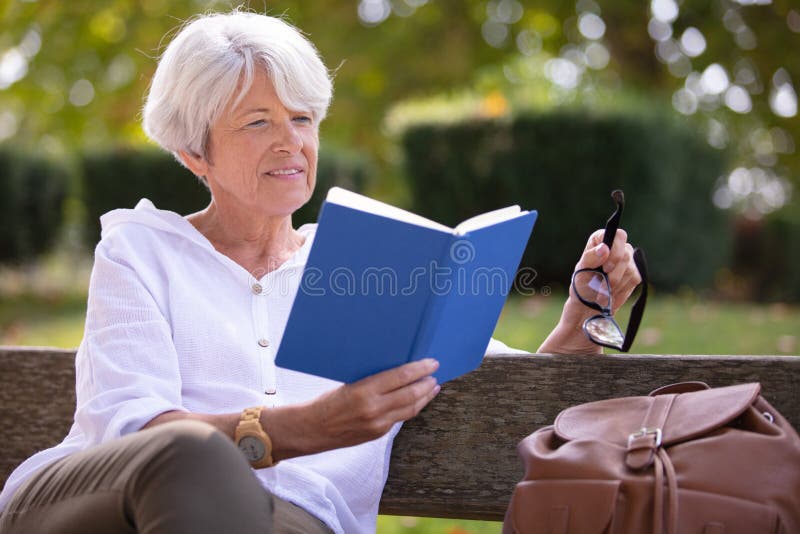 Retired Woman Reading Book on Bench Stock Image - Image of senior ...