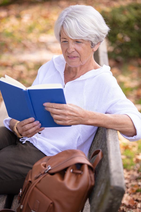 Retired Woman Reading Book on Bench Stock Photo - Image of sitting ...