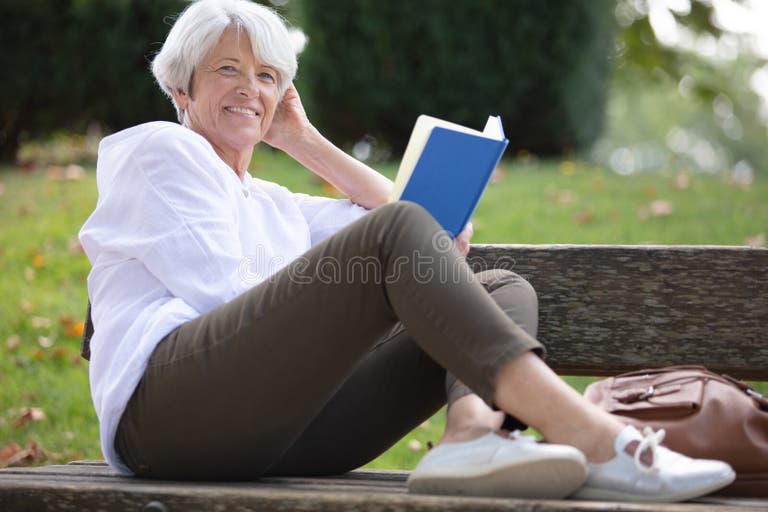 Retired Woman Reading Book on Bench Stock Image - Image of happy, piggy ...