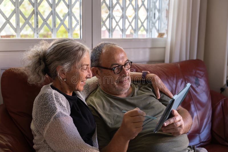 Retirees Relaxing at Home, Using a Tablet Together Stock Photo - Image ...