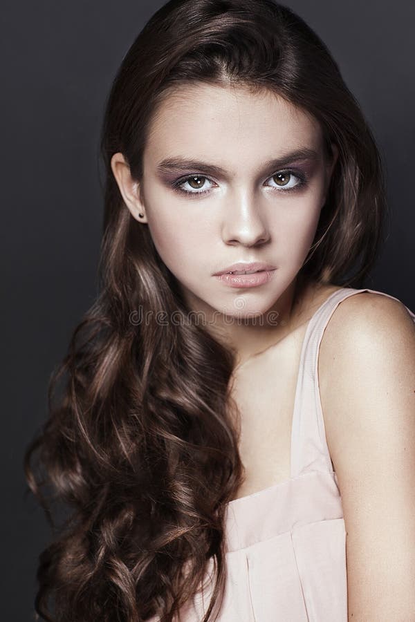 Retrato Hermoso De La Chica Joven Con El Vestido Largo Del Rosa Del Ib Del Pelo Rizado En Fondo