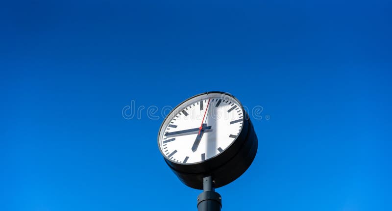 Round Clock on Black Pole Isolated on Bright Blue Sky Stock Image ...