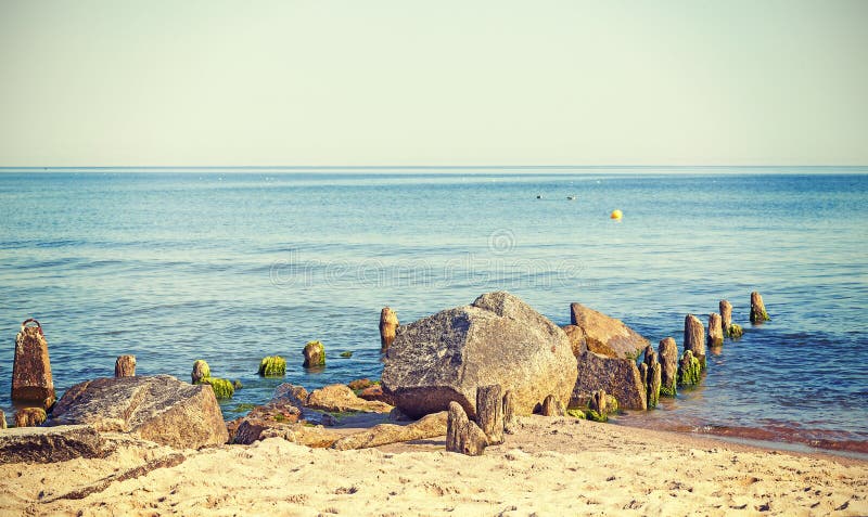 Retro Toned Rocks and Wooden Posts on the Beach. Stock Photo - Image of ...