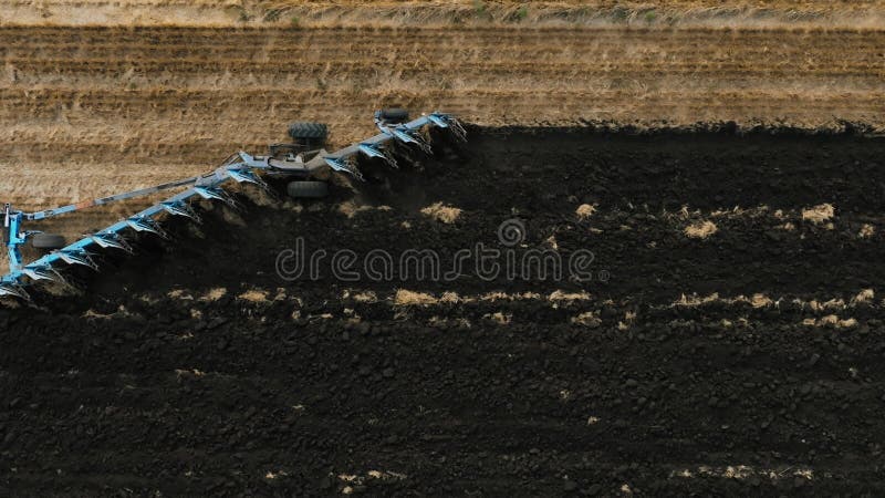 Reversible Plow on Support Wheels Moving Behind a Tractor in an Field ...