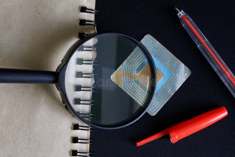 RFID Tag Transponder Under a Magnifying Glass, Next To a Pen and ...