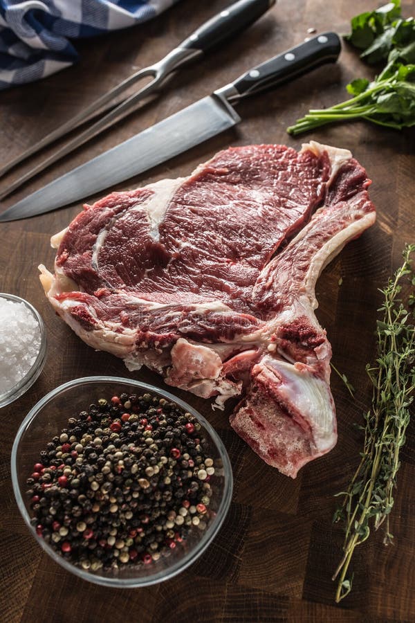 Rib Eye Steak with Bone on Butcher Board with Herbs Salt Pepper Fork ...