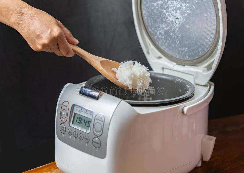 Rice Cooking in Electric Rice Cooker and Scoop Ladle Stock Photo ...