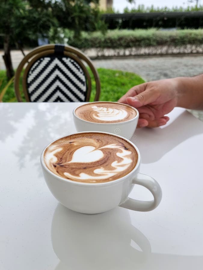 The Right Hand Holding One of Two Cups of Hot Latte Art Coffee while ...