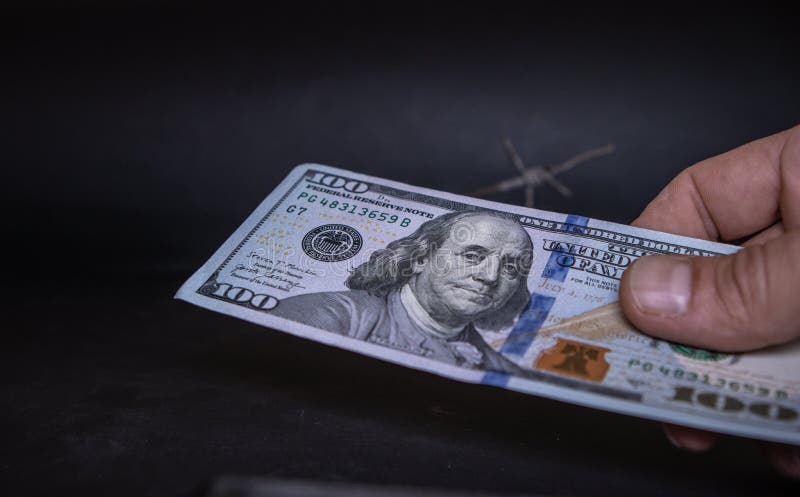 Right Hand Holds Stack of 100 Dollar Banknotes on Black Background, the ... Right Hand Holds Stack of 100 Dollar Banknotes on Black Background, the ...