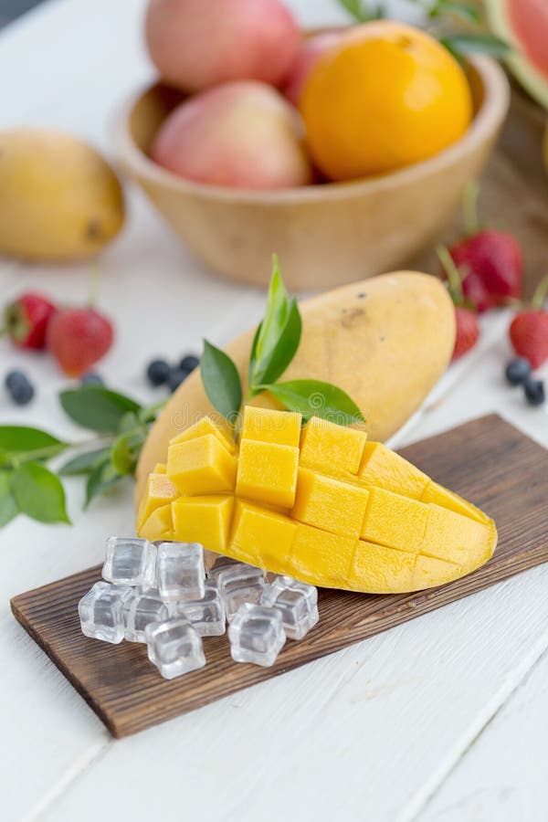 Ripe Mango on a Wooden Plate with Ice Cubes and Fruit As Background ...