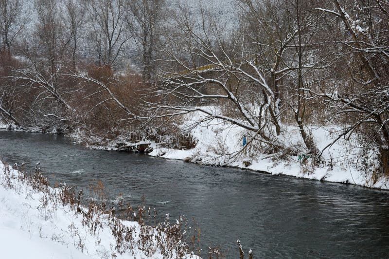 On the Bank of a Winter River, a Man and a Woman in Jackets are Sitting ...