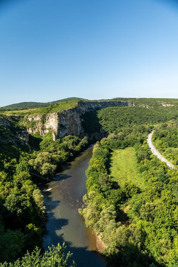 River Flowing through Lush Green Valley with Cliffs and Blue Sky Stock ...