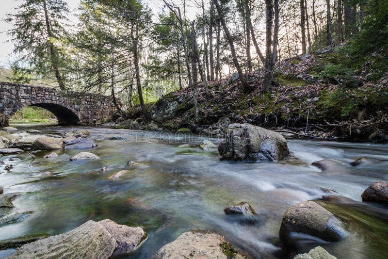 River Flows Gently Along Rocks Near an Arched Stone Bridge Stock Image ...