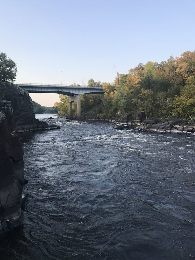 A River Flows Quickly Under a Bridge with Trees Along the Far Shoreline ...