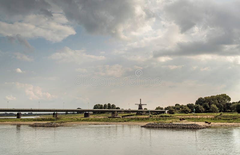 River IJssel with Bridge and Windmill Under Cloudy Sky. Overijssel ...