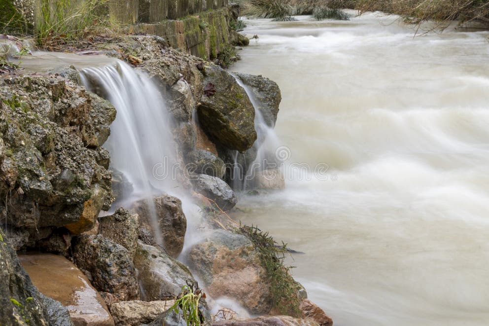 A River with a Waterfall and Rocks in the Background Stock Image ...