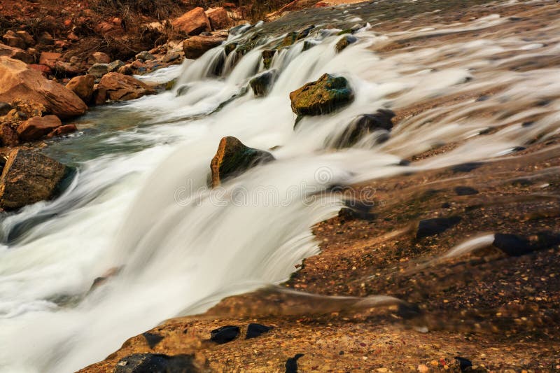 A River with a Waterfall and Rocks in the Background Stock Photo ...