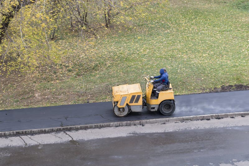 Road Construction Worker Compactes Fresh Steaming Asphalt with Roller ...