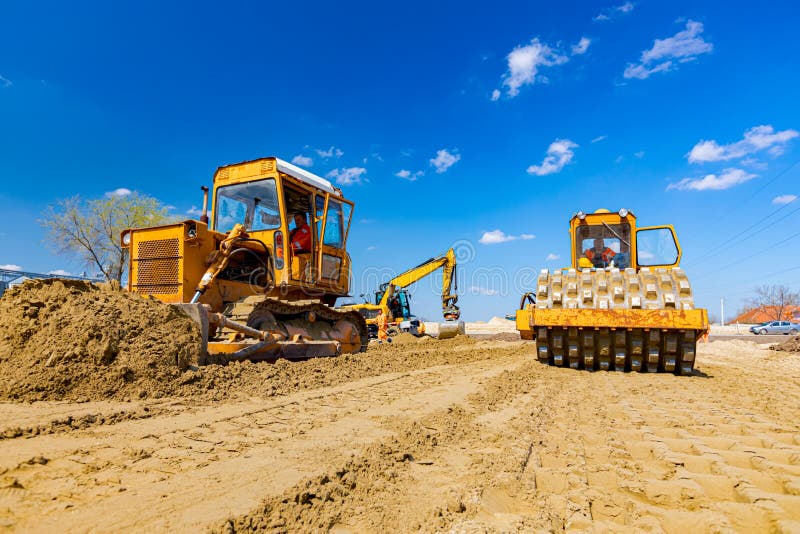 Road Roller with Spikes and Earthmover are Working at Construction Site ...