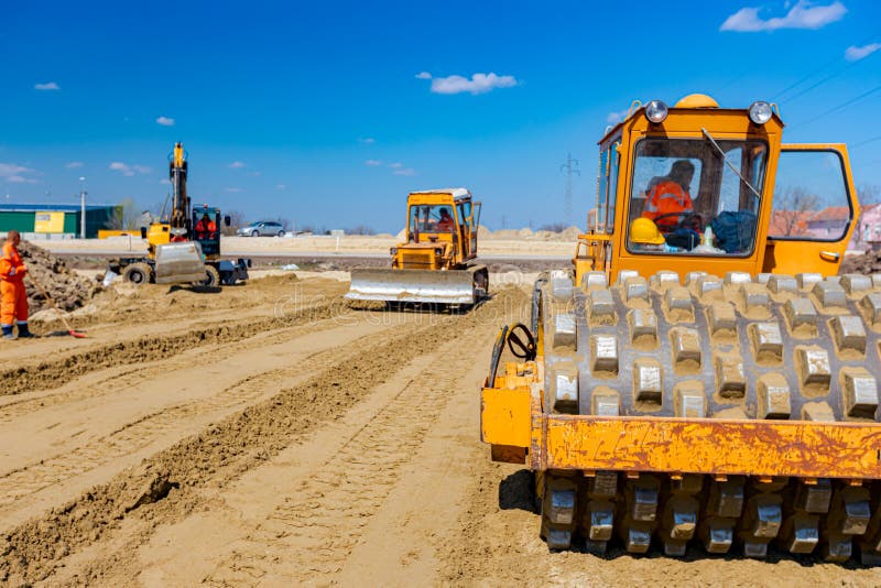 Road Roller with Spikes and Earthmover are Working at Construction Site ...