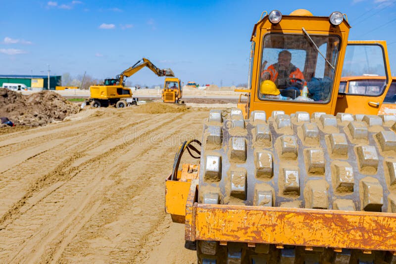 Road Roller with Spikes and Earthmover are Working at Construction Site ...