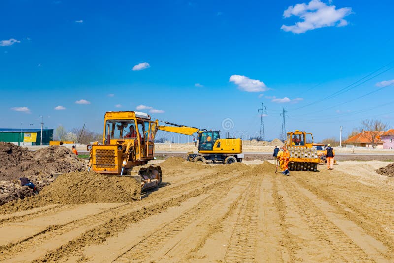 Road Roller with Spikes and Earthmover are Working at Construction Site ...