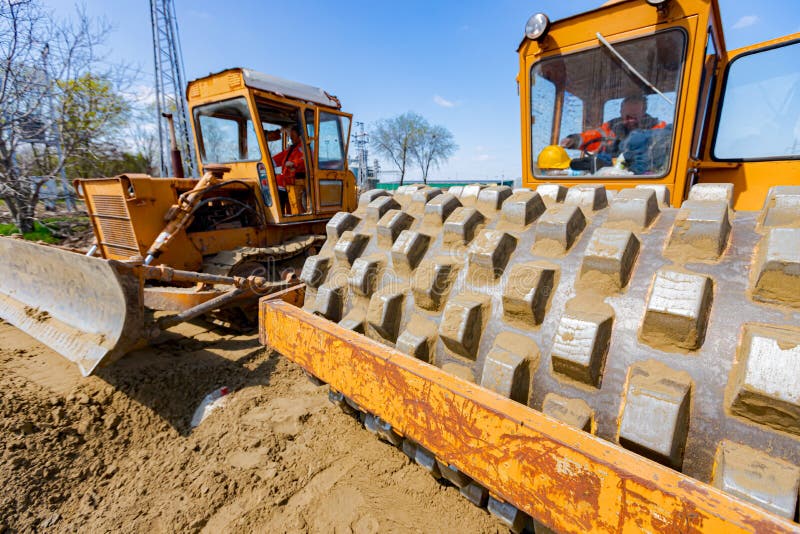 Road Roller with Spikes and Earthmover are Working at Construction Site ...