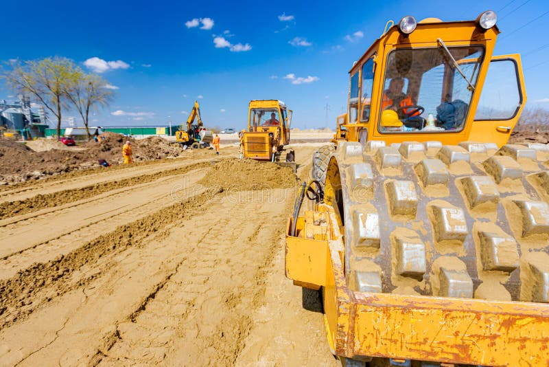 Road Roller with Spikes and Earthmover are Working at Construction Site ...