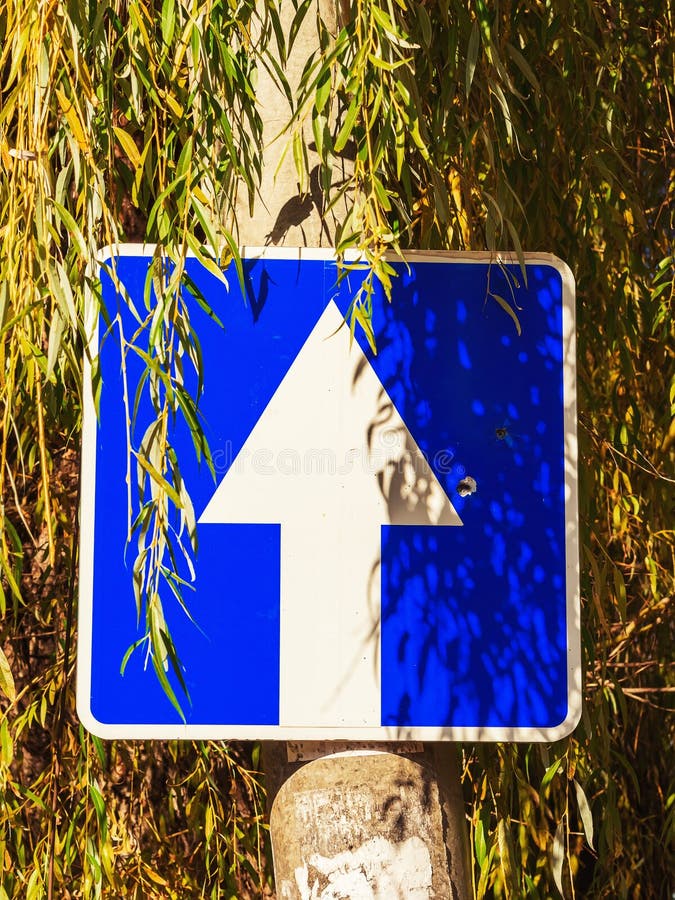 A Road Sign with a White Arrow in a Blue Square is Located on a Pole in ...