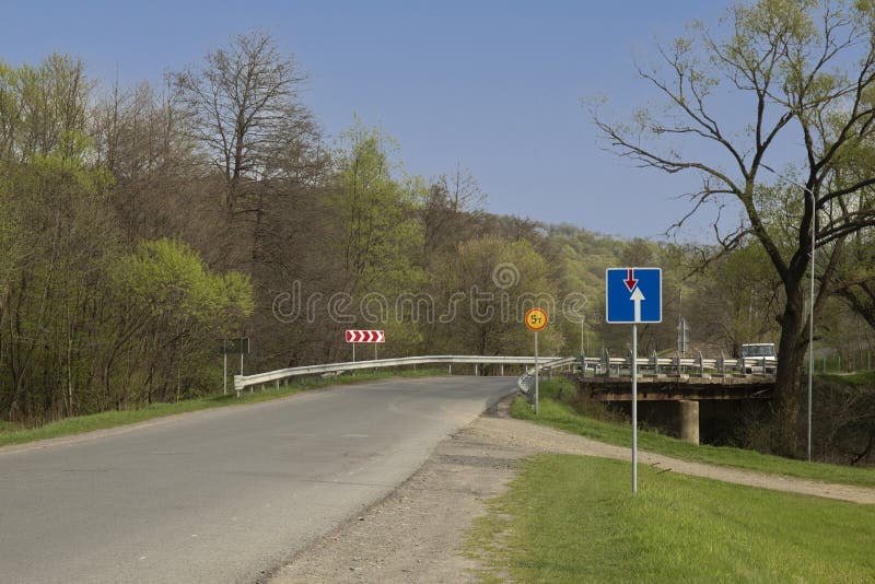 Road Signs in Road before Bridge Across the River Stock Photo - Image ...