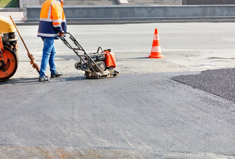A Worker Compacts Soil or Sand with a Vibrating Plate in a Trench at a ...