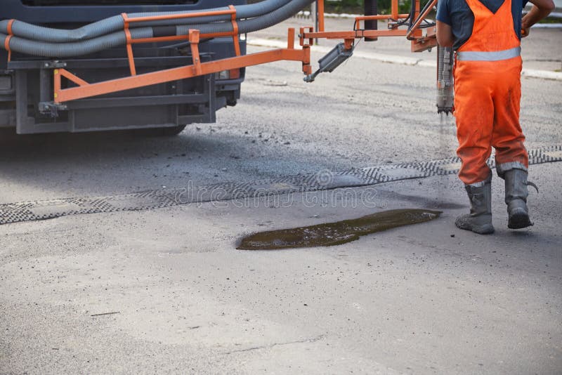 Road Worker Repairing Asphalt Coating, Using a Manipulator. Pitching ...
