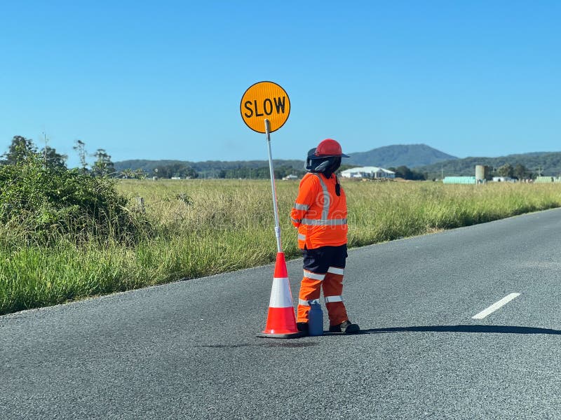 Road Worker Stand beside a Slow Down Traffic Sign Stock Image - Image ...