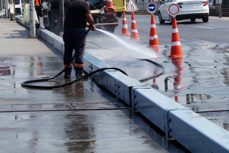 Road Worker Washing the Roadway with Water from a Hose Stock Image ...