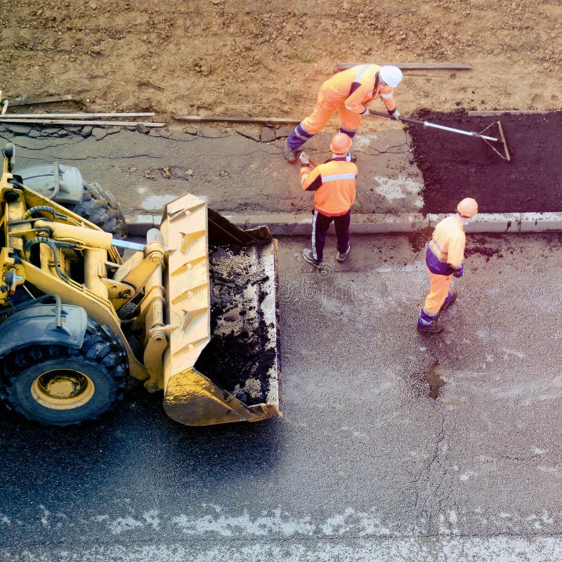 Road Workers Level the Asphalt on the Ground with Shovels and Lay it ...