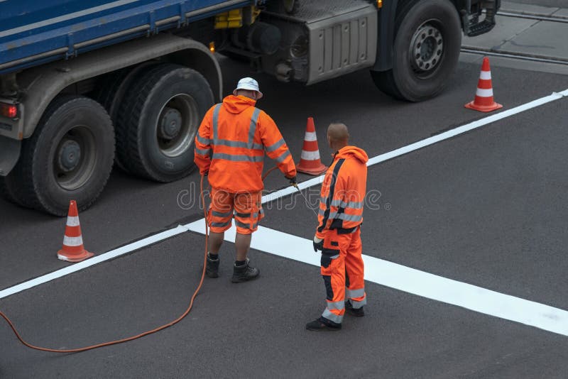 Road Workers in Orange Uniforms Renovate Road Markings Stock Image ...