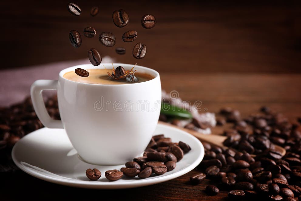 Roasted Beans Falling into Cup with Aromatic Coffee on Wooden Table ...