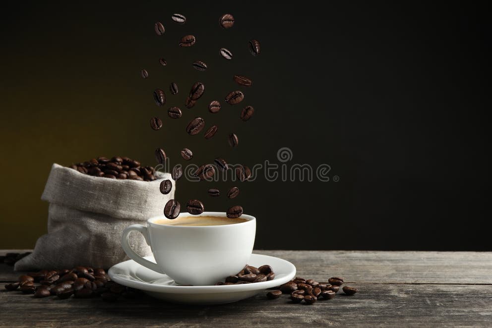Roasted Beans Falling into Cup with Aromatic Coffee on Wooden Table ...
