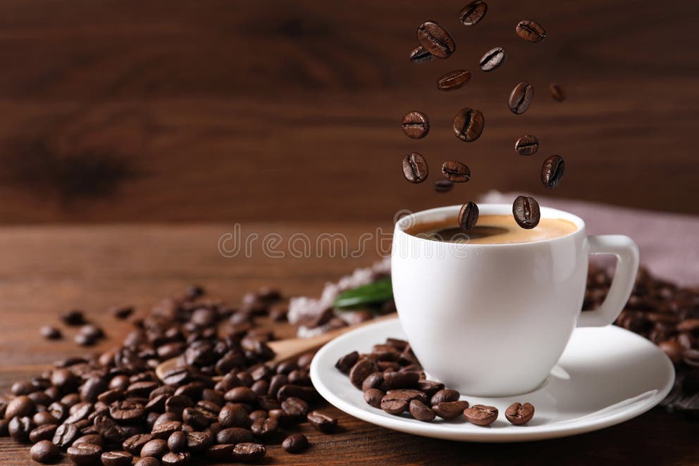Roasted Beans Falling into Cup with Aromatic Coffee on Wooden Table ...