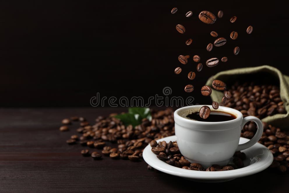 Roasted Beans Falling into Cup with Aromatic Coffee on Wooden Table ...