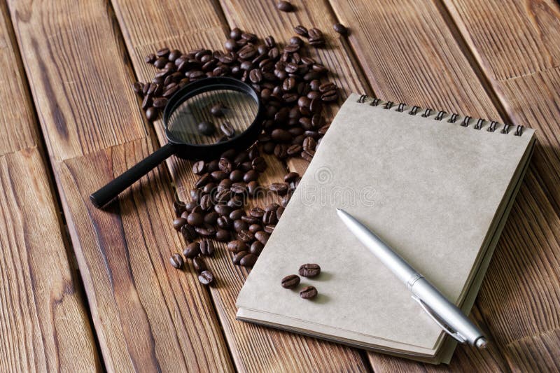 Roasted Coffee Beans, Notepad, Magnifier and Pen on a Pine Plank Table ...