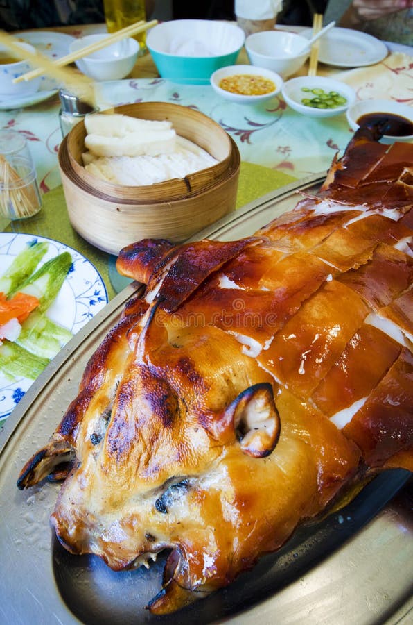 Roasted Piglet with Potato Chips and Orange on White Plate Stock Photo ...