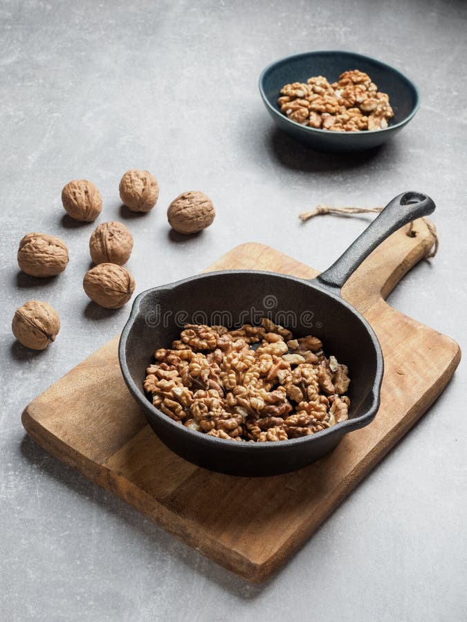 Roasted Tasty Walnuts in Black Pan on Cutting Board Against Concrete ...
